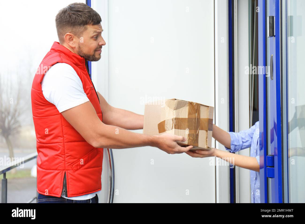 Emotional courier giving damaged cardboard box to client outdoors. Poor ...