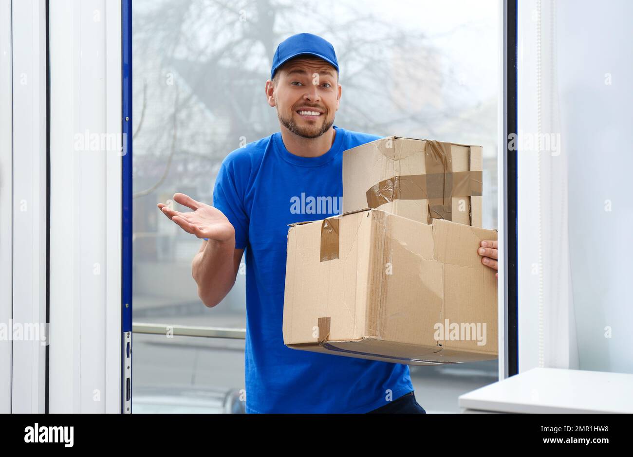 Emotional courier with damaged cardboard boxes in doorway. Poor quality ...