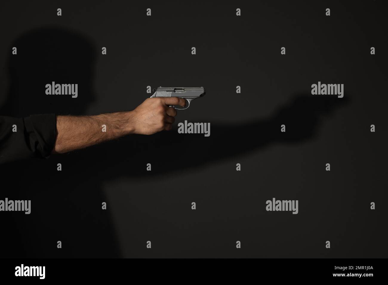 Professional killer with gun on black background, closeup Stock Photo ...
