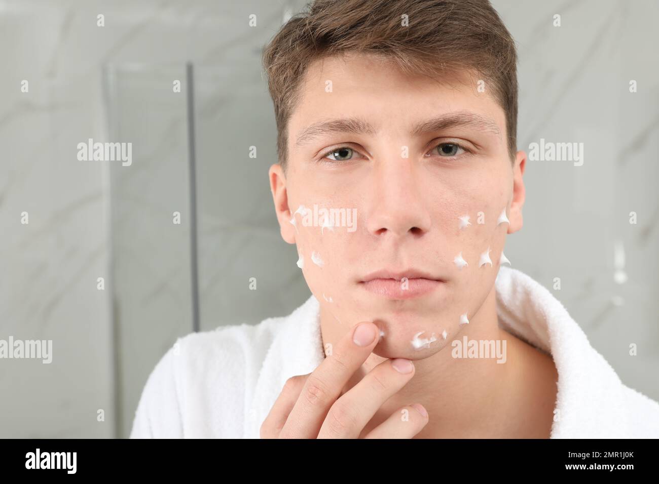 Teen guy with acne problem applying cream in bathroom Stock Photo - Alamy