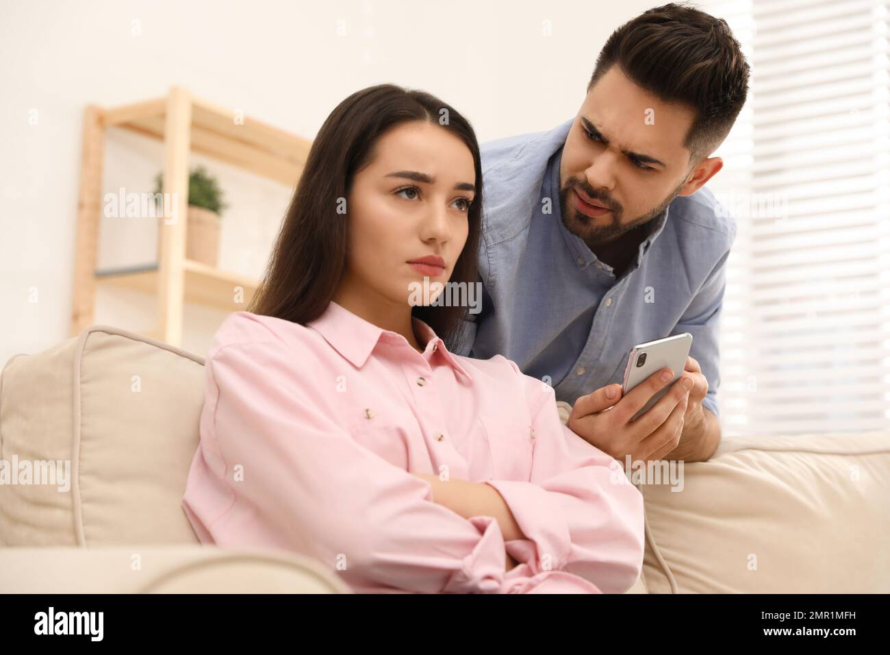 Young couple arguing about smartphone at home. Problems in relationship ...