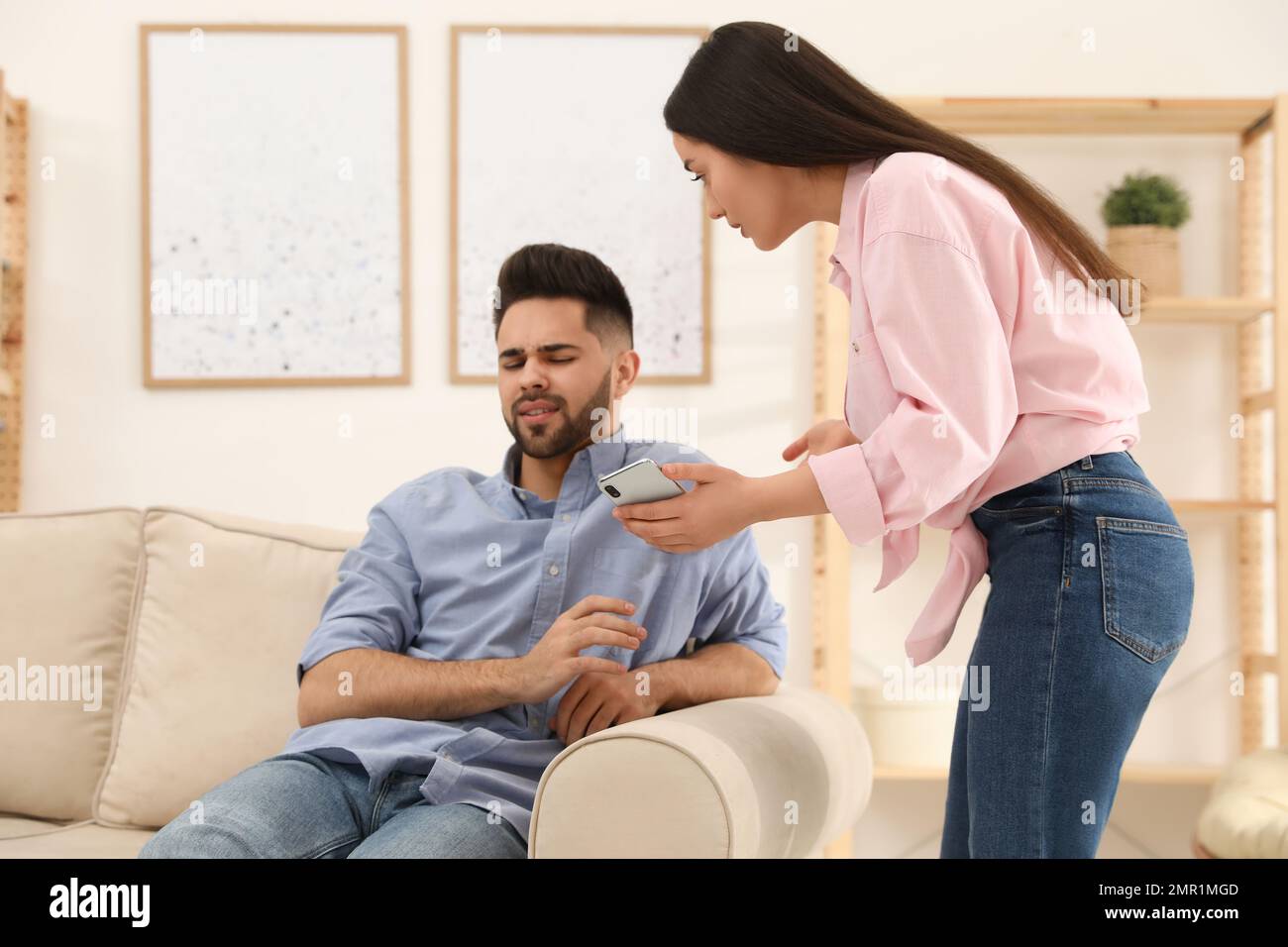 Young couple arguing about smartphone at home. Problems in relationship ...