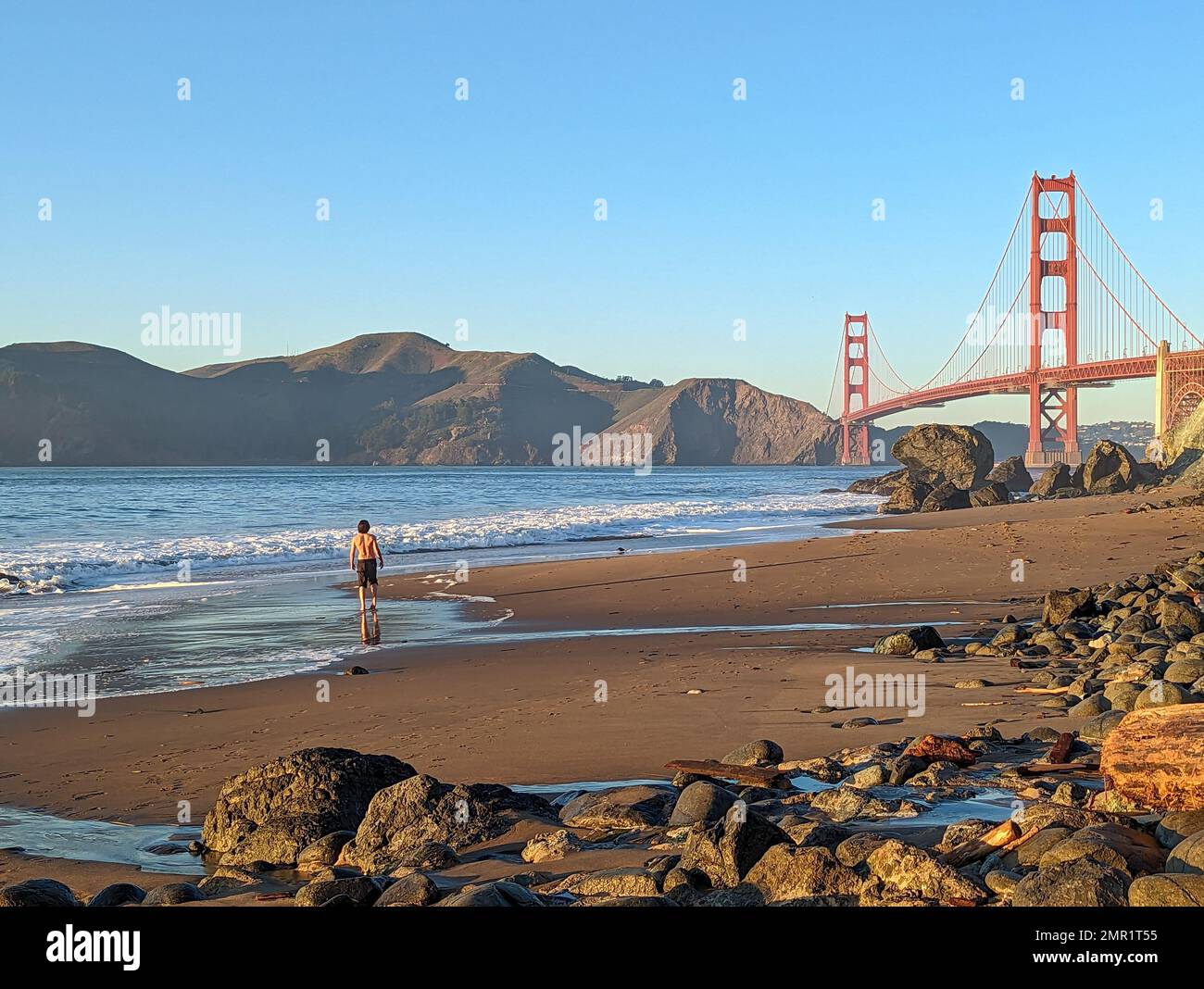 Lone man walking on Marshall's beach at sunset with the Golden Gate ...