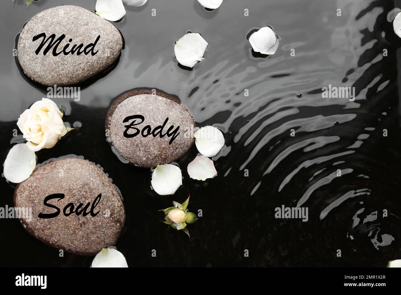 Spa stones with words Mind, Body, Soul and rose petals in water, flat ...