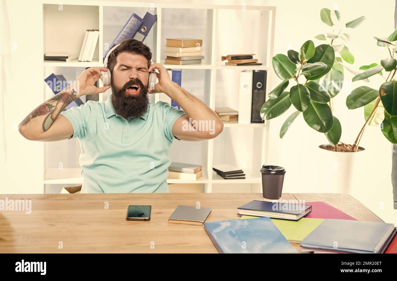 Happy man singing along while listening to song in headphones in office ...