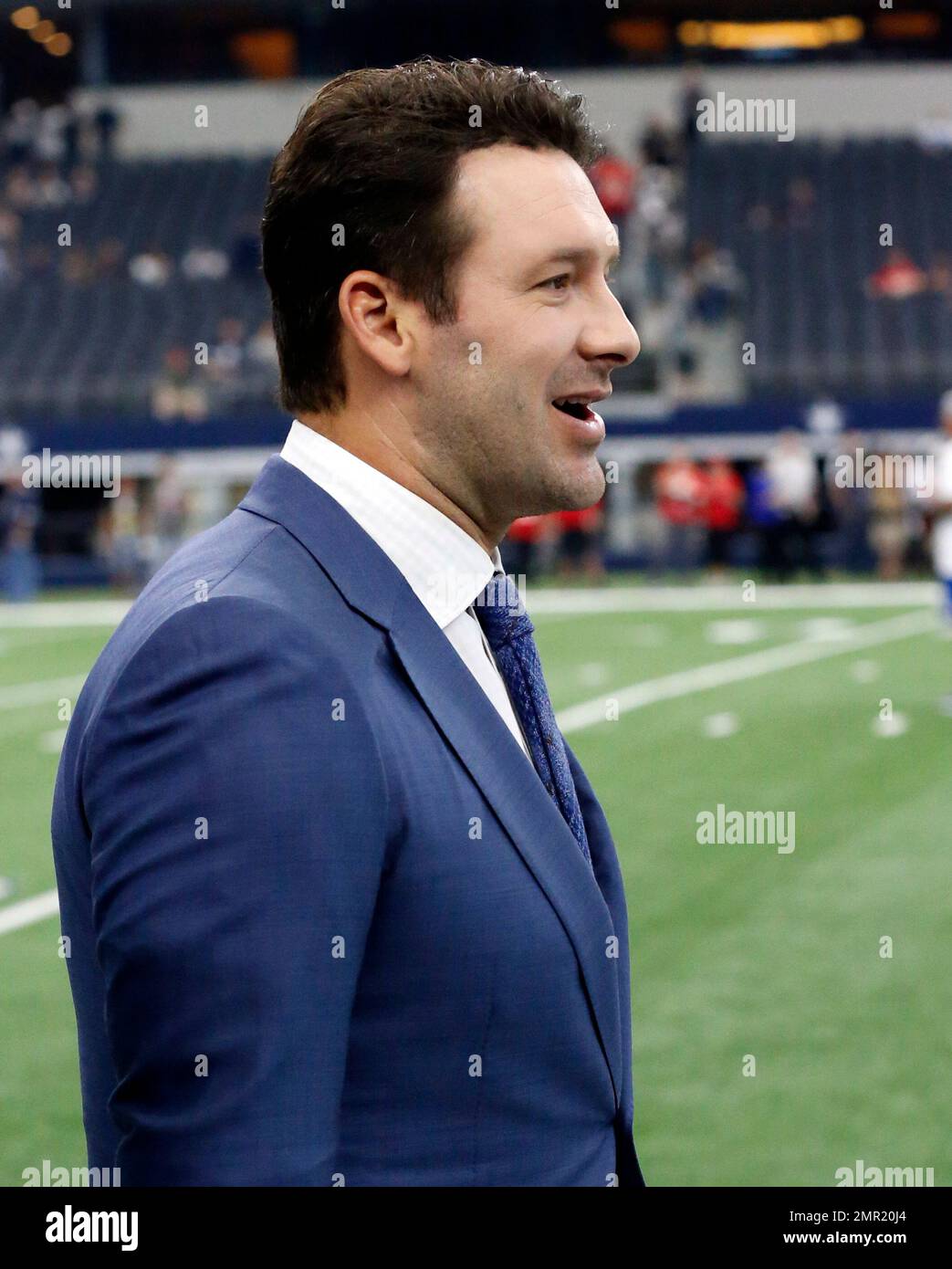 Broadcast analyst Tony Romo walks along the sideline before an NFL ...