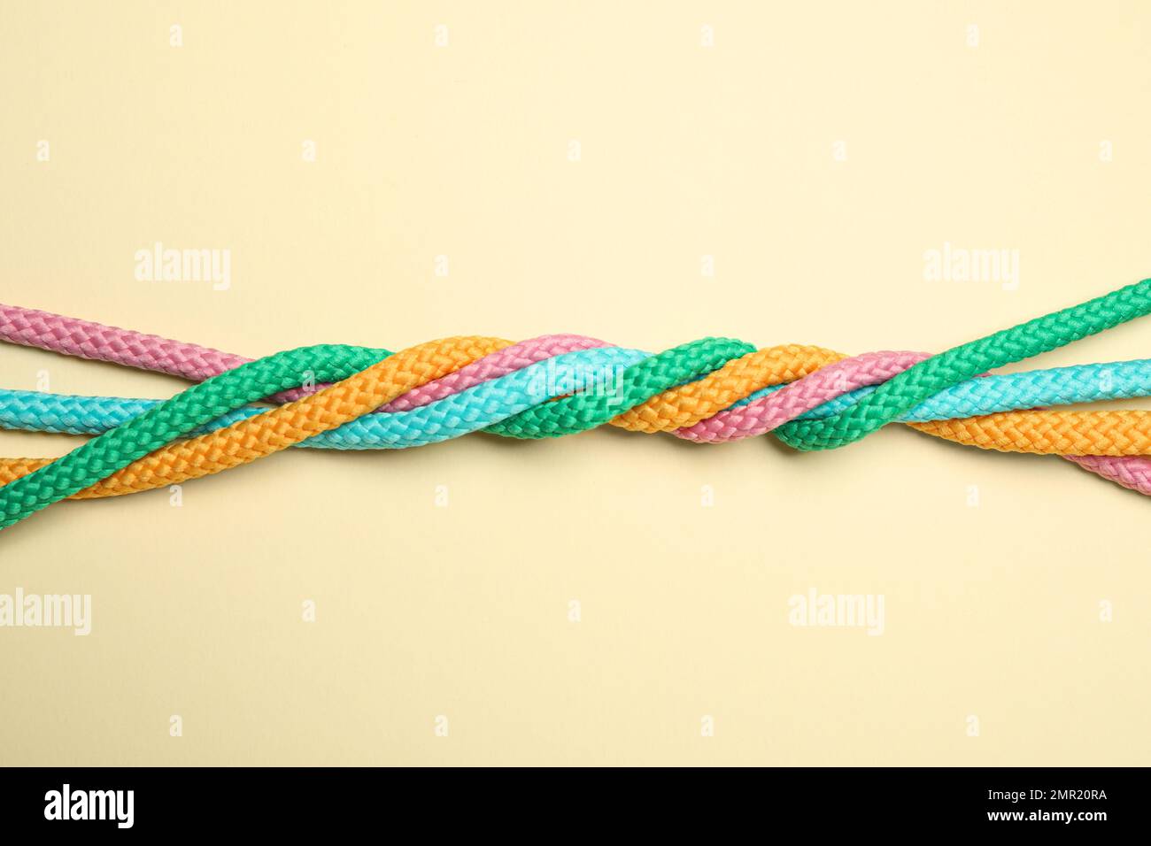 Twisted colorful ropes on beige background, top view. Unity concept ...