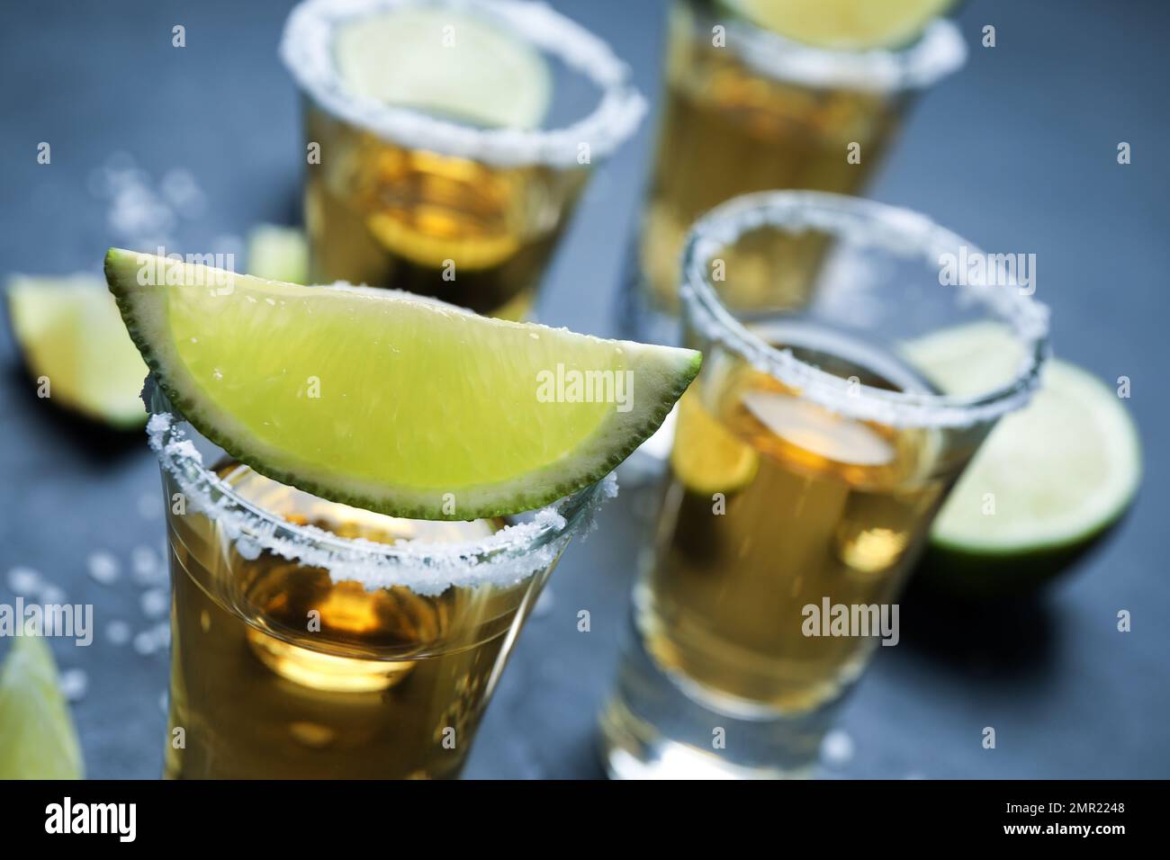 Mexican Tequila shots with salt and lime slices on grey table, closeup ...