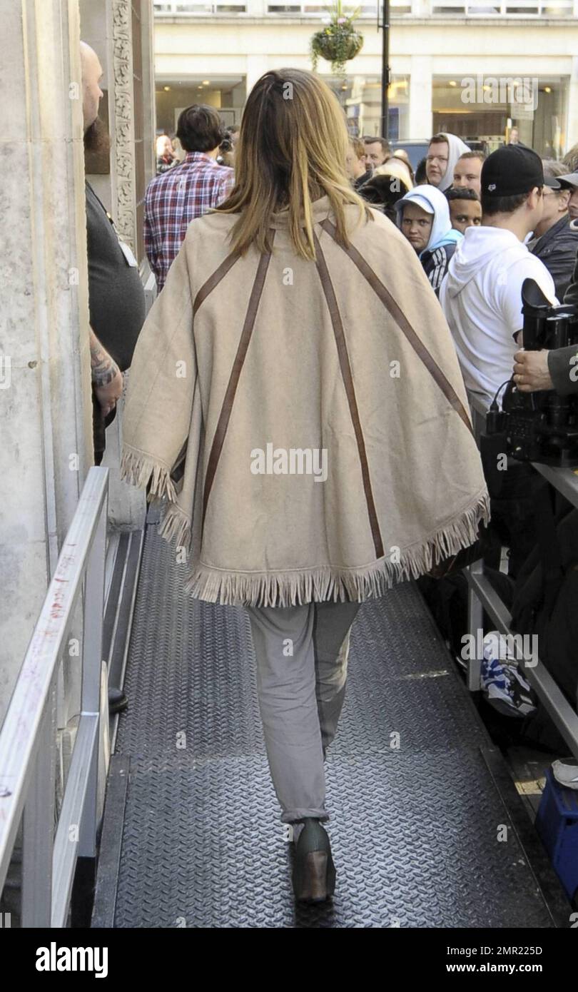BBC Radio 1 DJ Fearne Cotton wears a tan cape over her grey outfit and carries a shiny gold ...