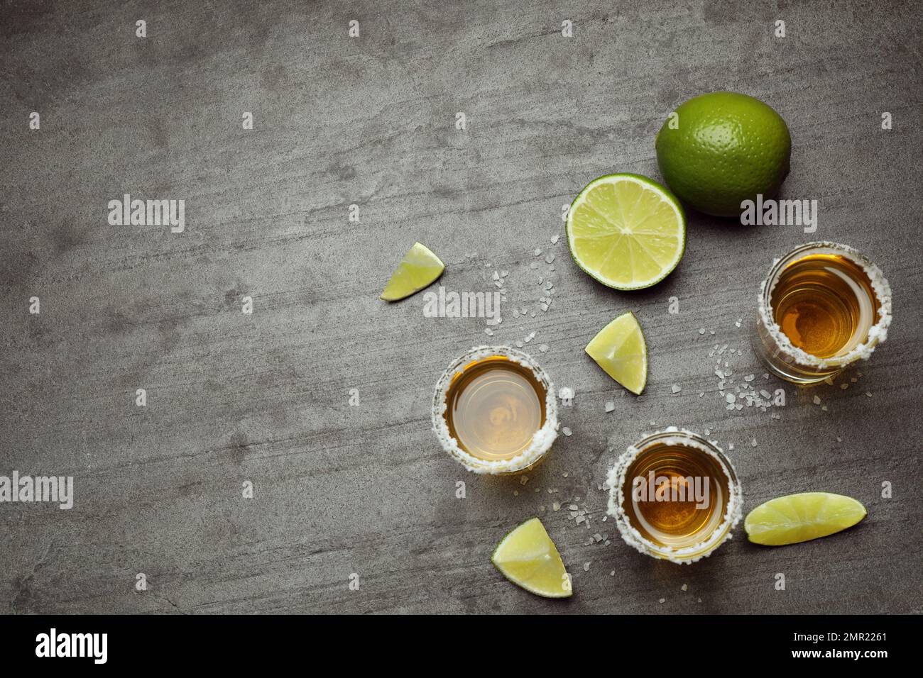 Mexican Tequila shots, lime slices and salt on grey table, flat lay ...