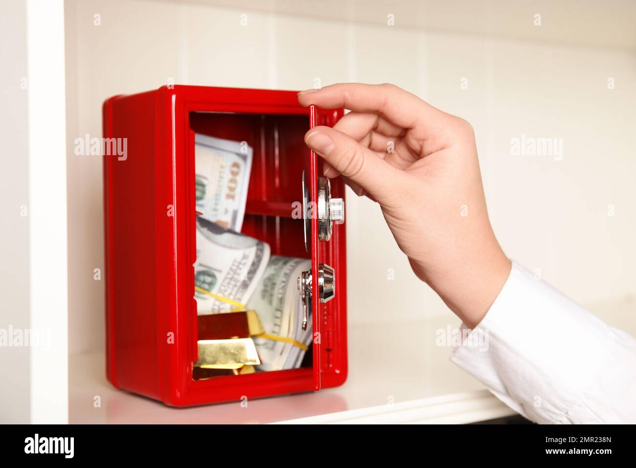 Woman opening red steel safe on shelf, closeup Stock Photo - Alamy