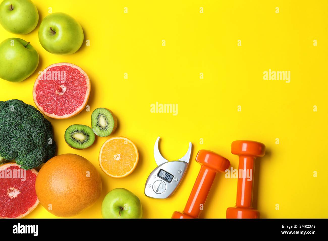 Fruits, vegetables, dumbbells and digital caliper on yellow background ...