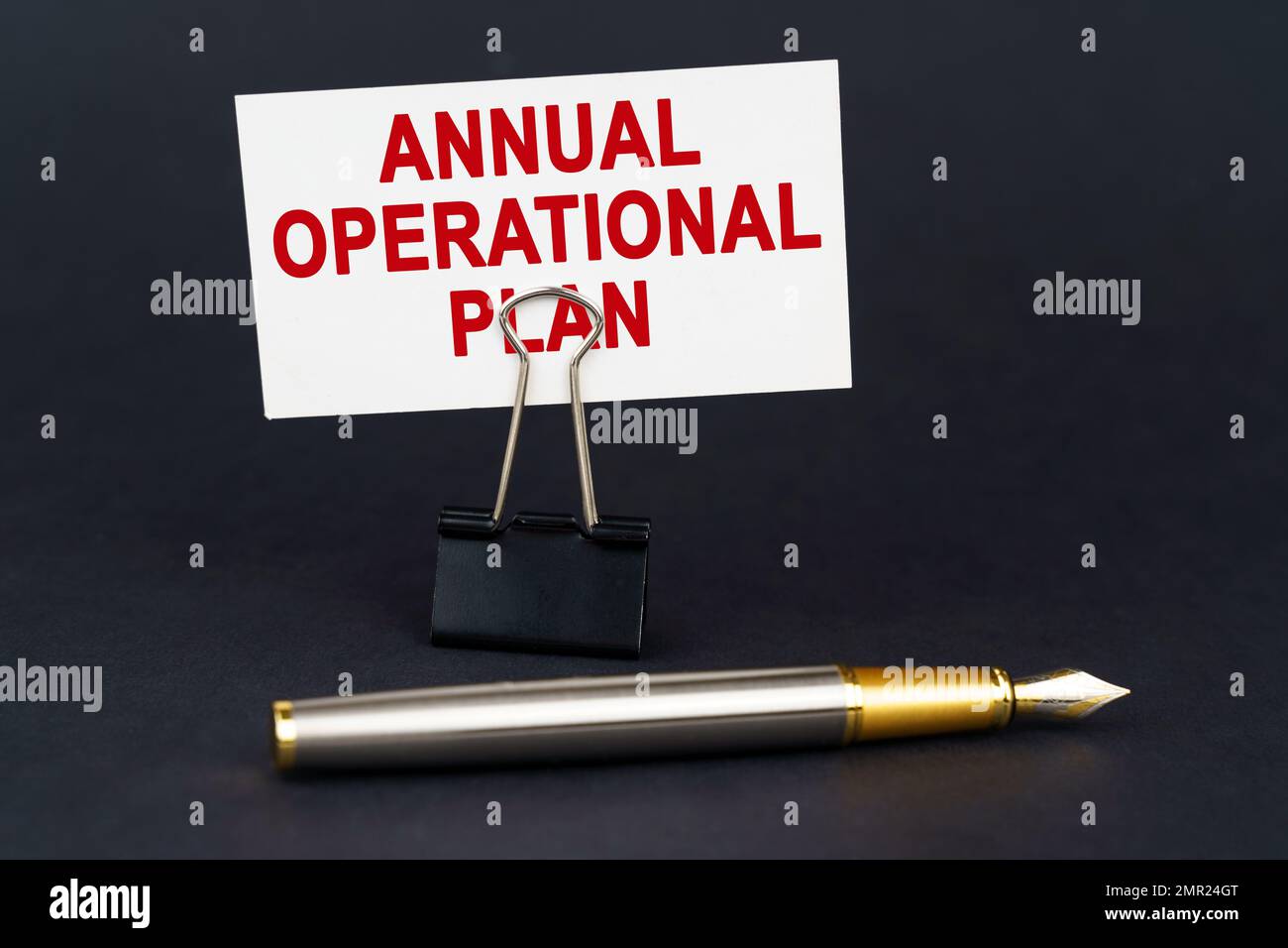 Business concept. On the black surface is a pen, an office paper clip ...