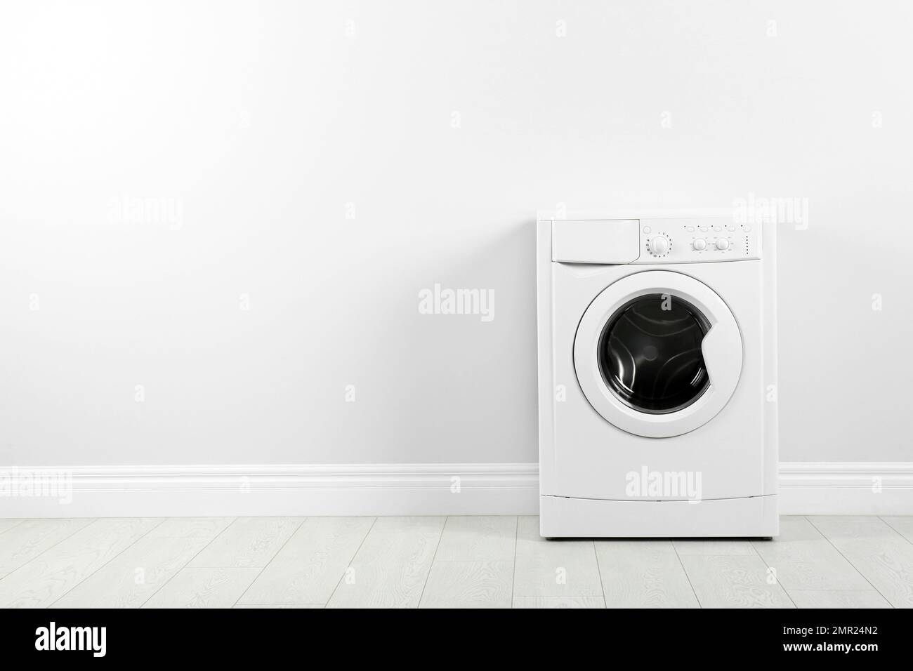 Modern washing machine near white wall, space for text. Laundry day ...