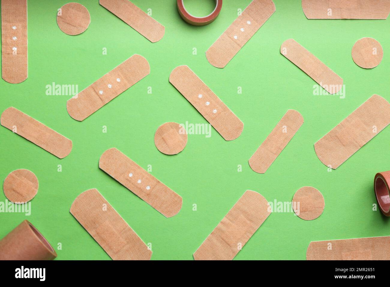 Different types of sticking plasters on green background, flat lay ...