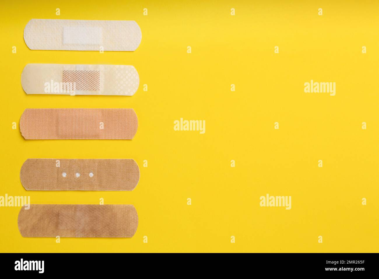Different types of sticking plasters on yellow background, flat lay ...