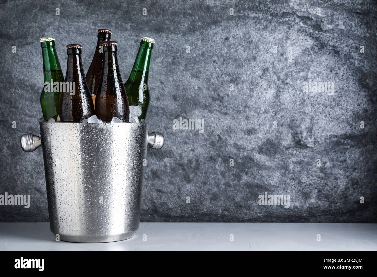 Beer in metal bucket with ice on light grey table. Space for text Stock ...