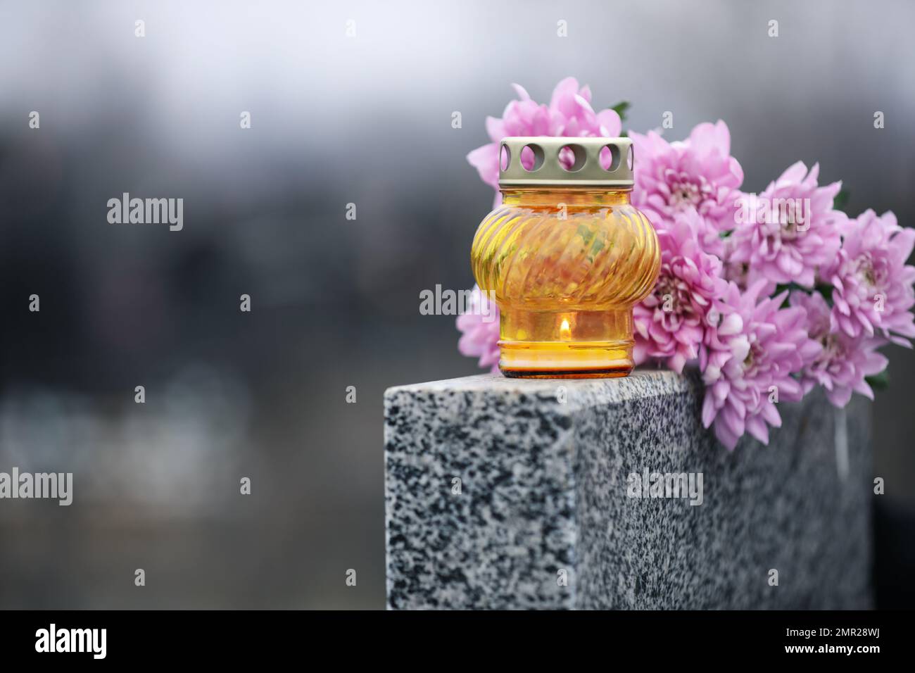 Chrysanthemum flowers and candle on grey granite tombstone outdoors. Funeral ceremony Stock ...