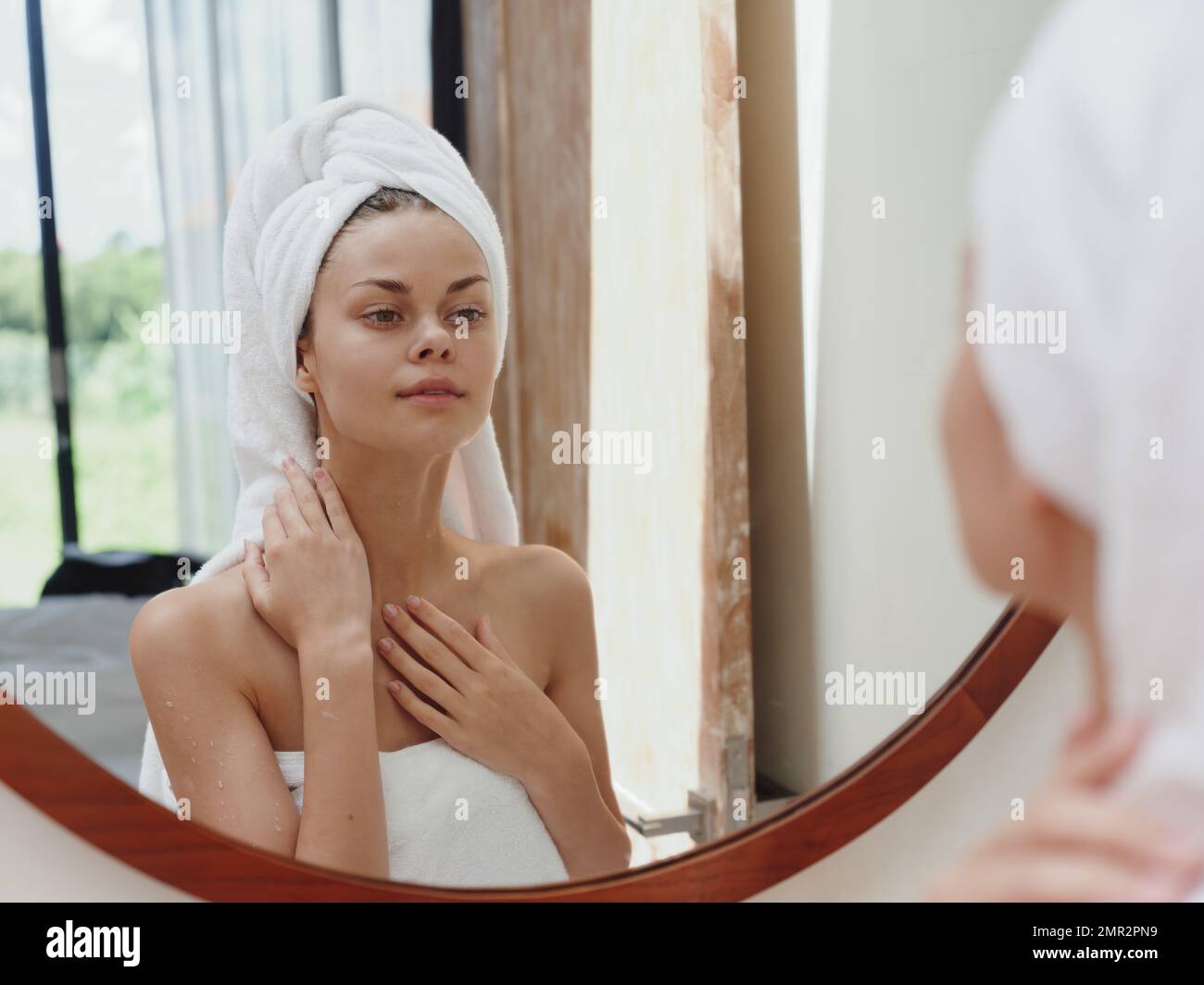 A beauty woman stands in front of a mirror looks at her reflection and ...