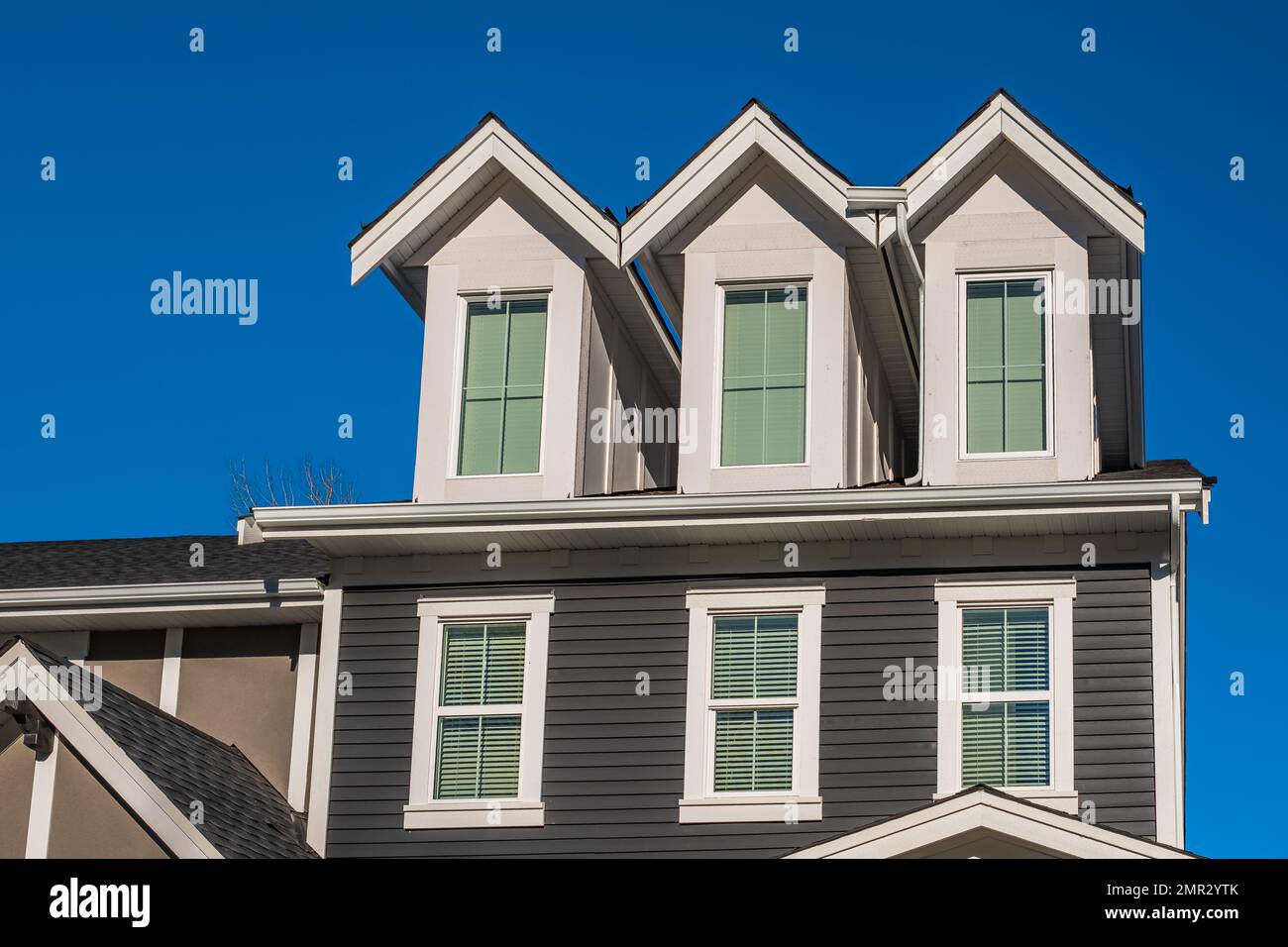 Top of a house with nice windows. Dormer in the blue sky background ...