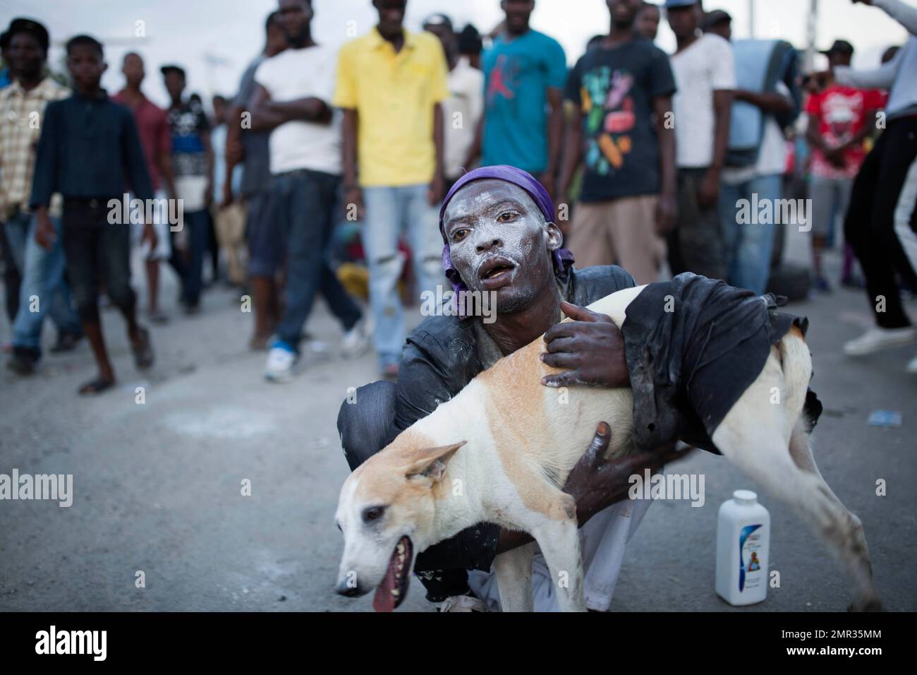 A man invokes a "Gede" spirit as he embraces his dog during Haiti's ...