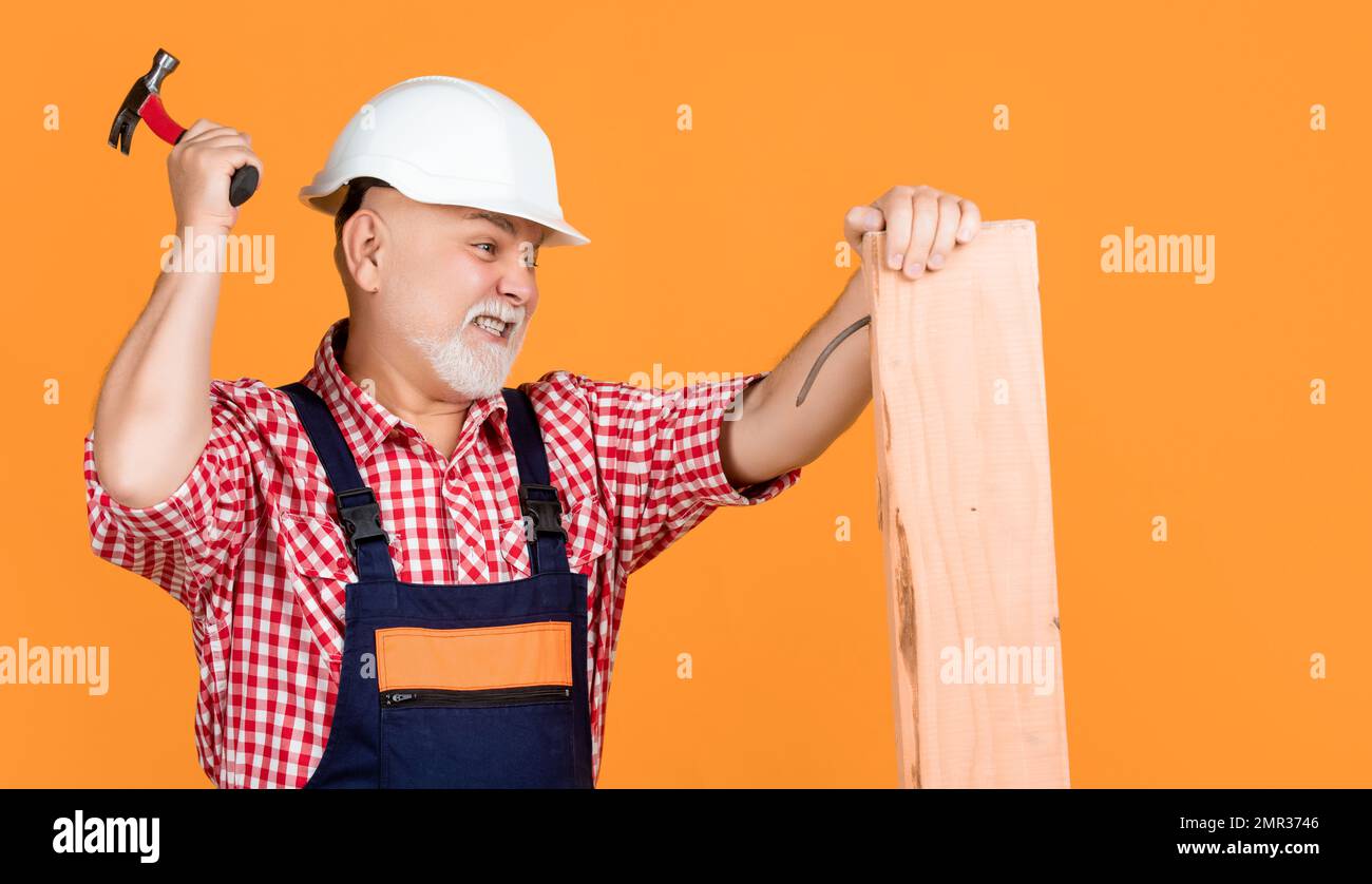 busy old man woodworker in helmet on yellow background Stock Photo - Alamy
