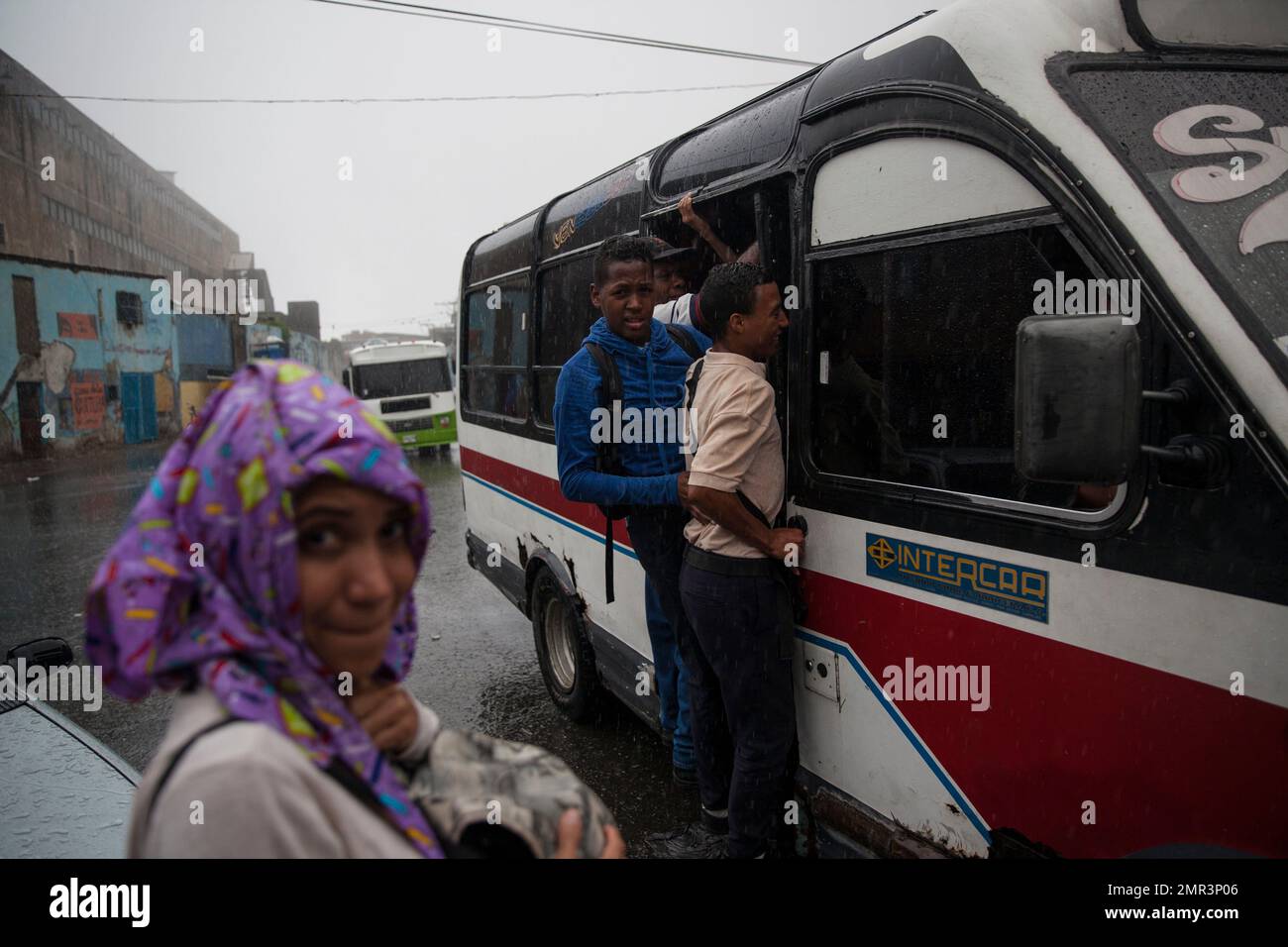 A woman waits in the rain for public transportation in the Catia ...