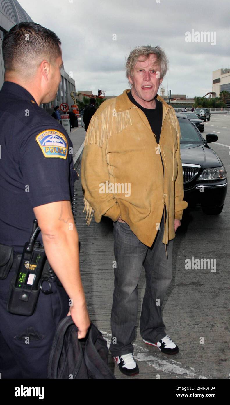 Looking a bit rough around the edges, actor Gary Busey waves to cameras ...