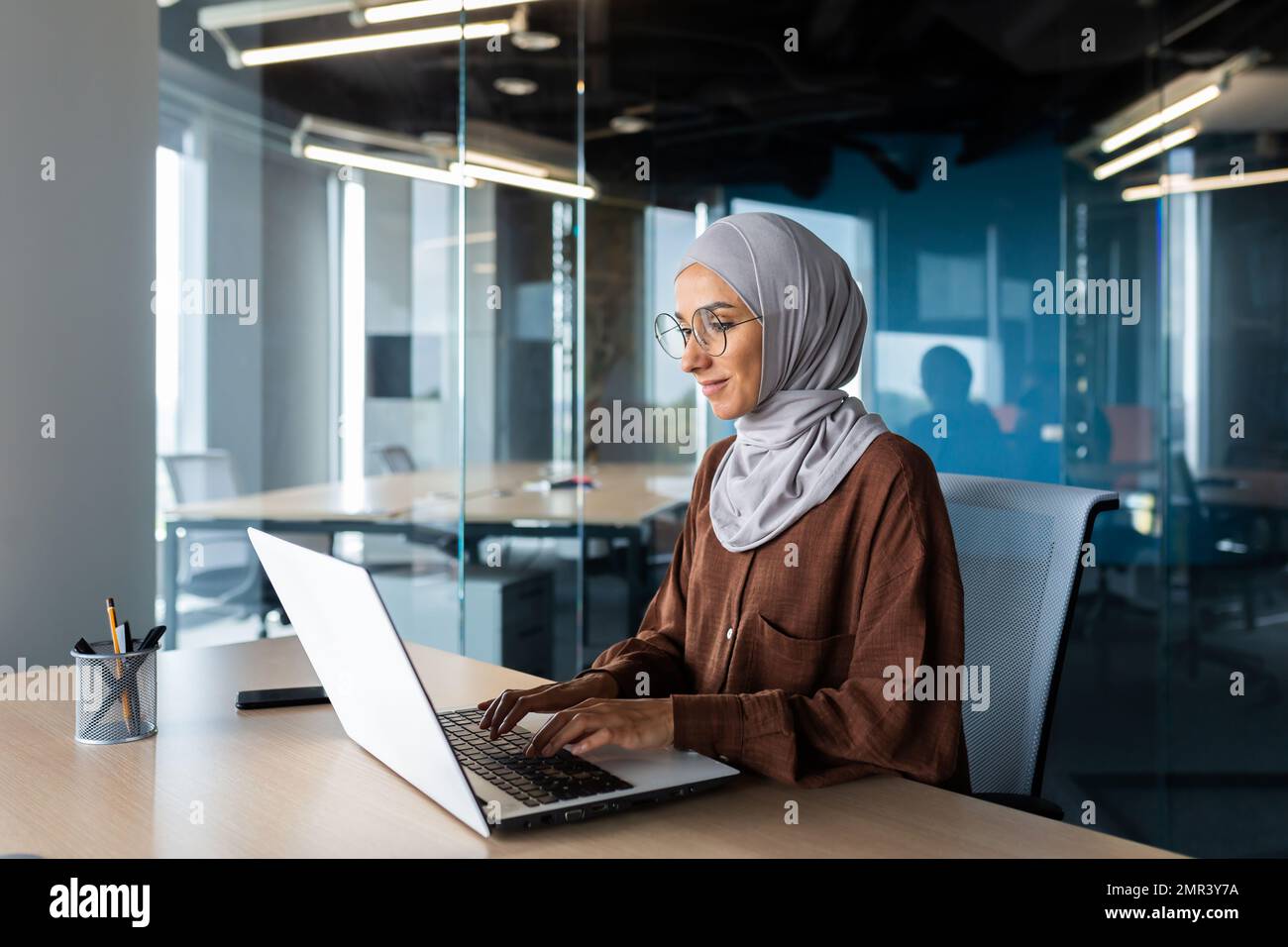 Successful smiling Arab woman in hijab working inside modern office ...