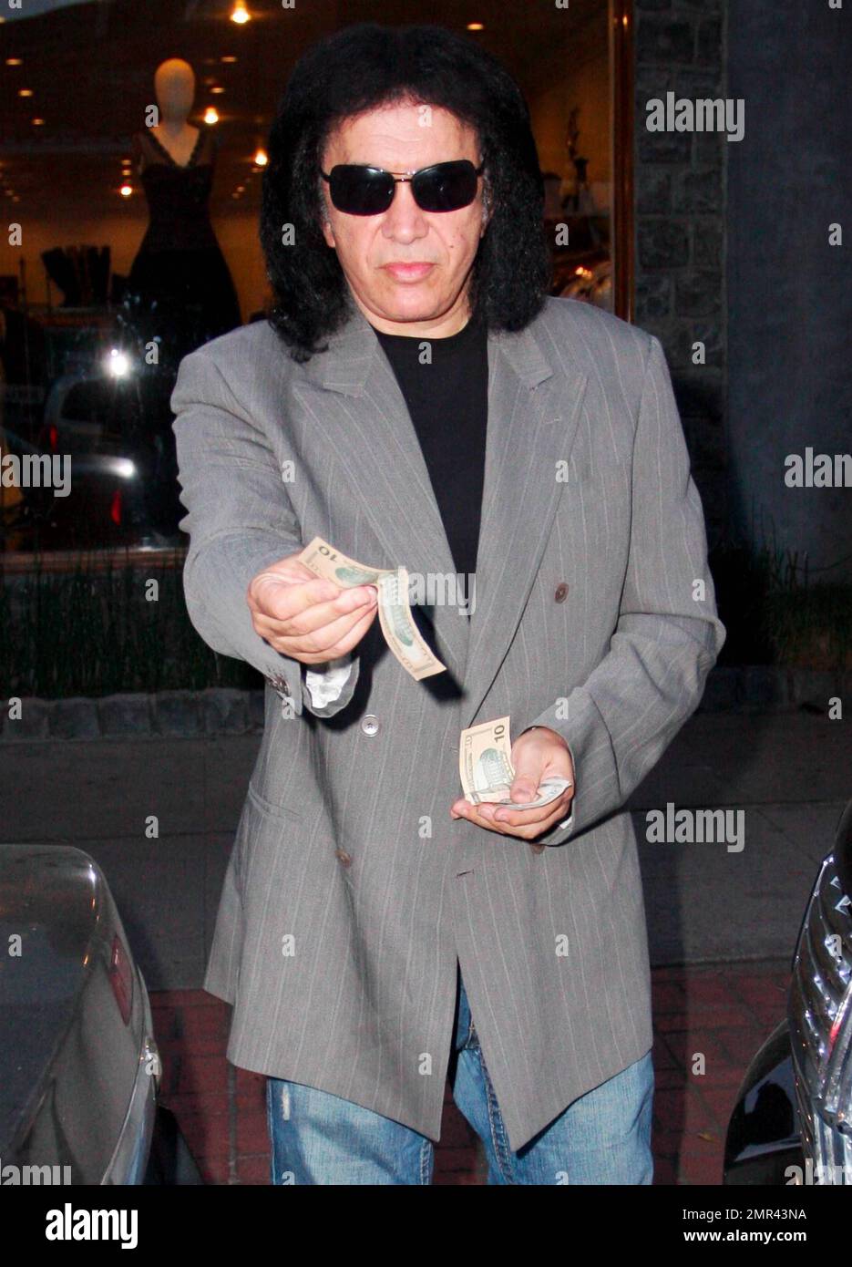 Rock star Gene Simmons playfully chomps down on a 10 dollar bill as he ...