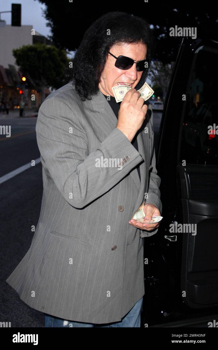 Rock star Gene Simmons playfully chomps down on a 10 dollar bill as he ...