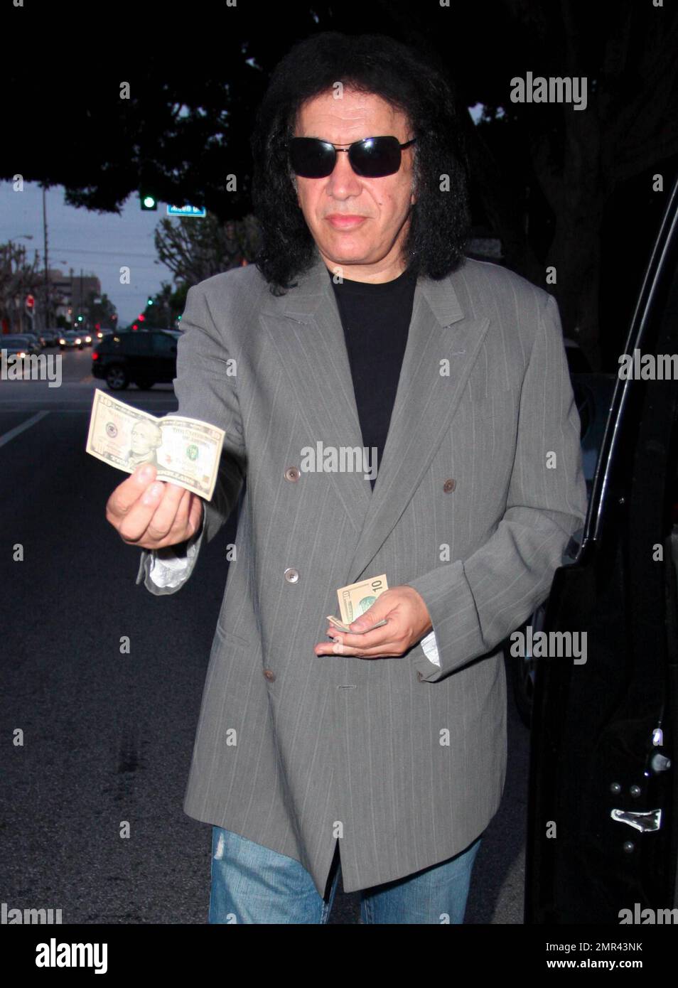 Rock star Gene Simmons playfully chomps down on a 10 dollar bill as he ...