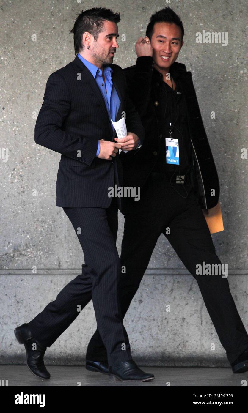 Colin Farrell buttons up his jacket on a snazzy suit and carries papers ...