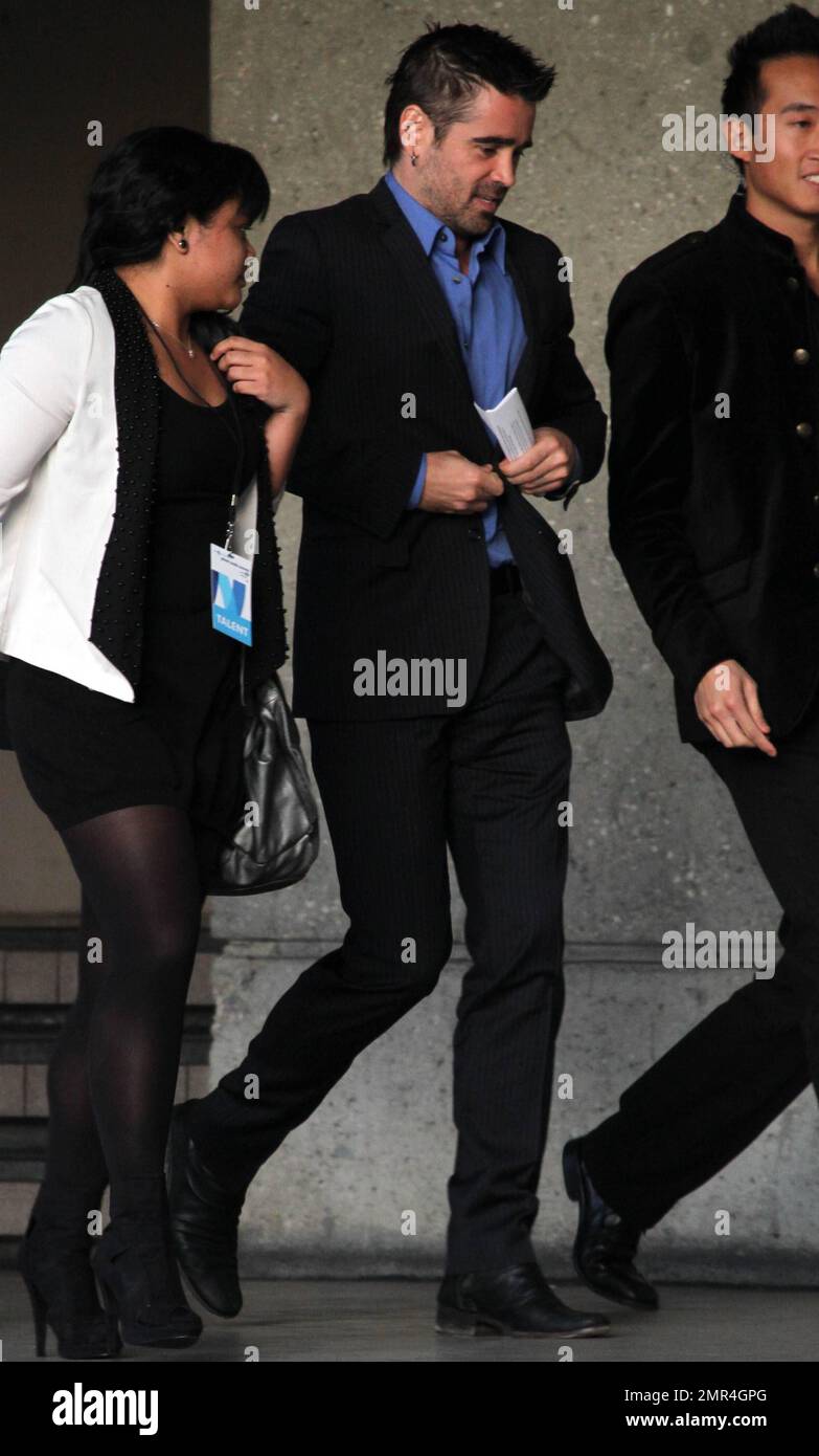 Colin Farrell buttons up his jacket on a snazzy suit and carries papers ...