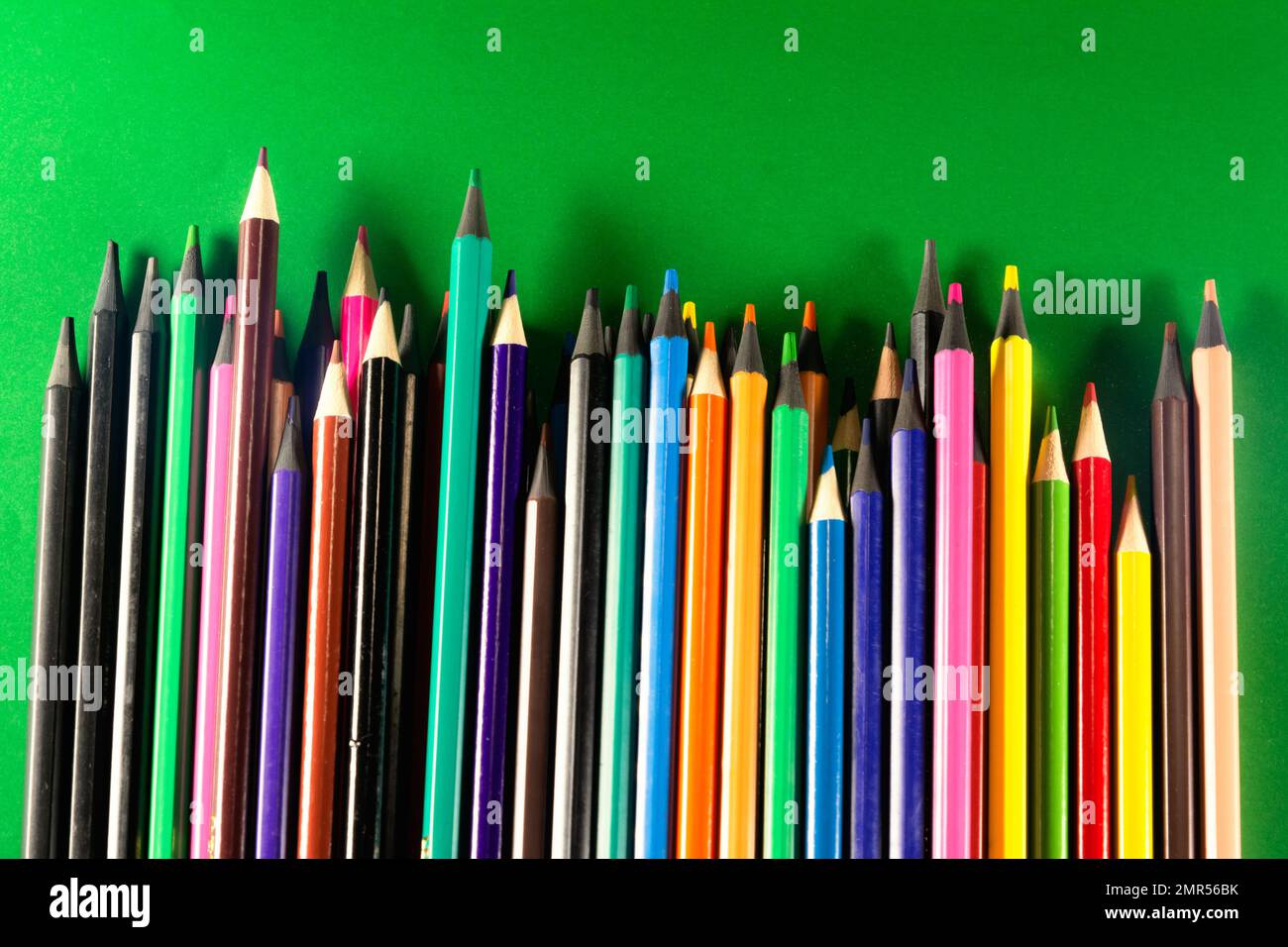 Stacked colored pencils. Isolated on green background. Close-up Stock ...