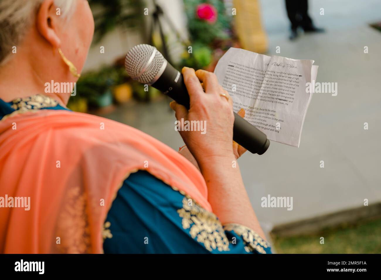 A close-up shot of an adult woman reading a speech with a microphone at ...