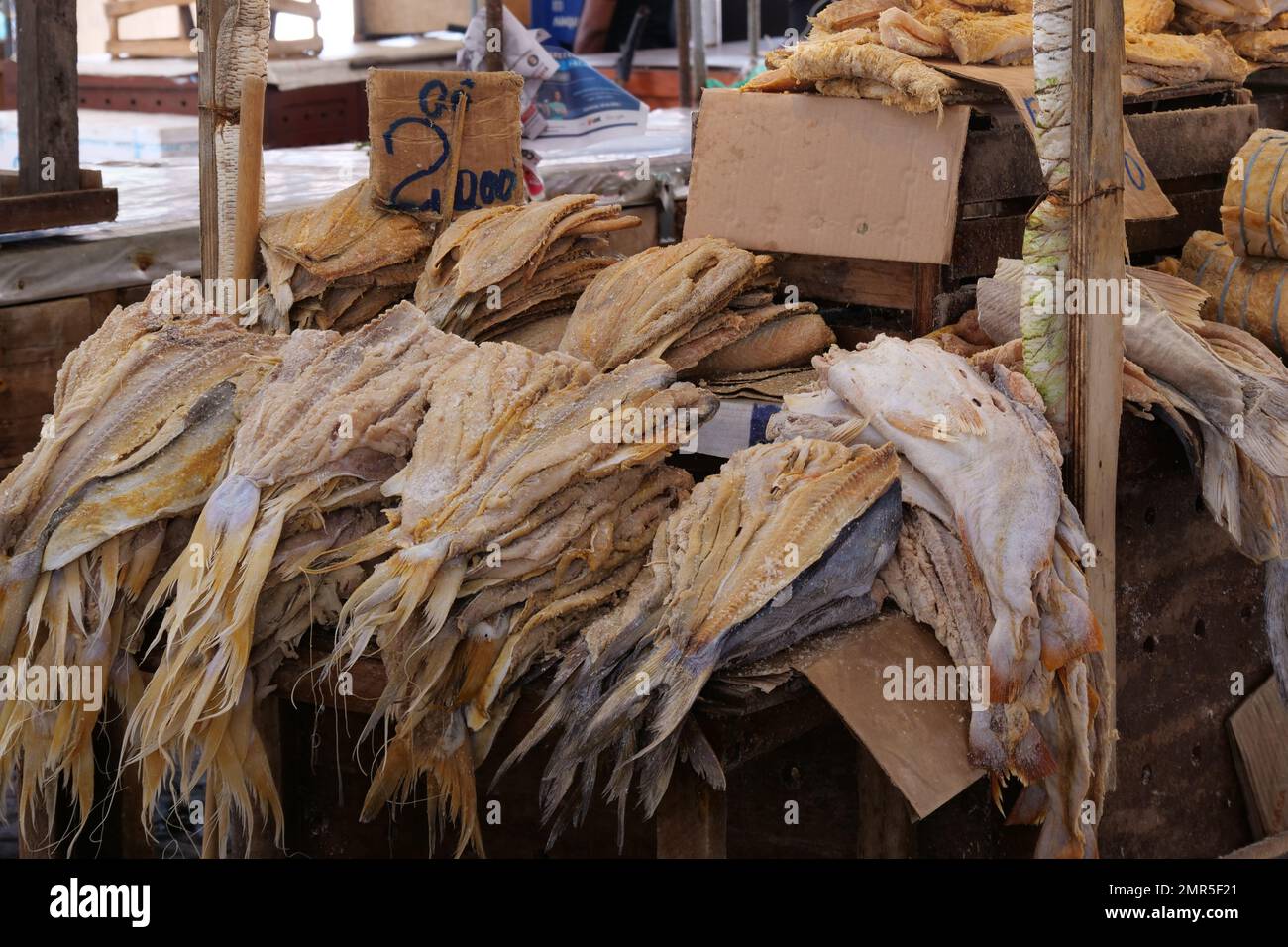 Pieces of whole and salted fish stacked in piles at a fish market at ...