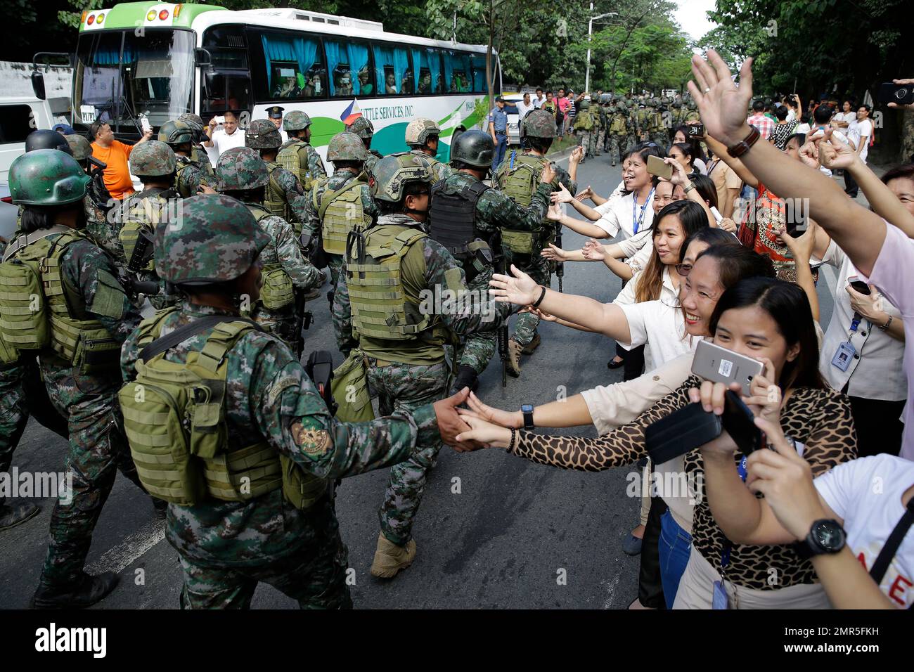 Residents and office workers welcome members of the Philippine National ...