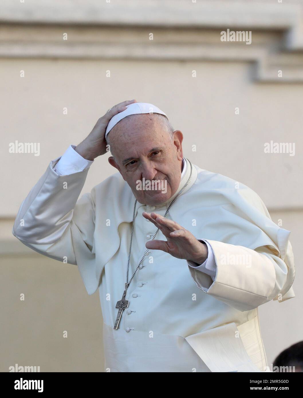 Pope Francis holds on to his skull cap as he waves upon his arrival for ...