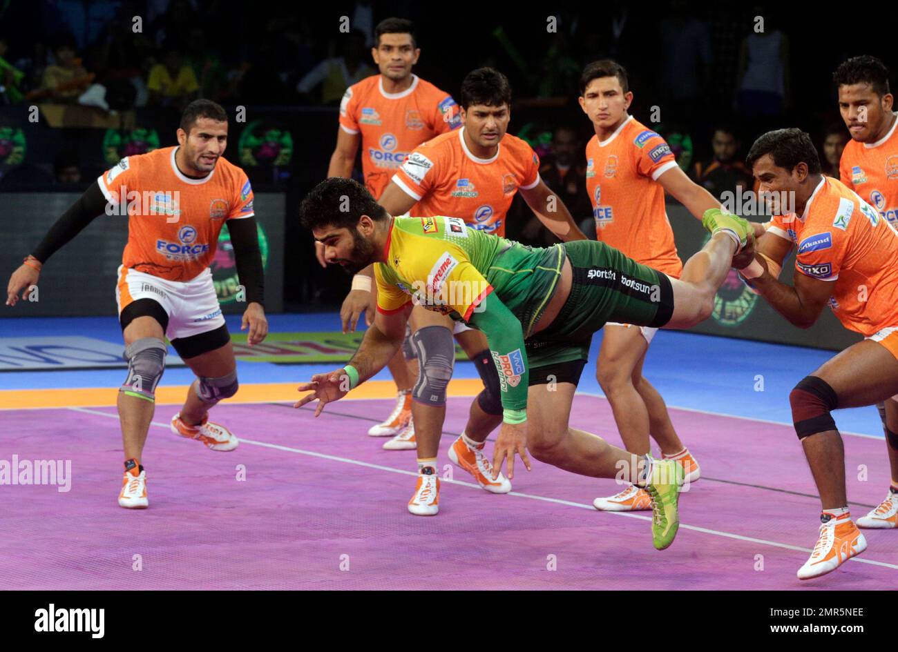 Players of Puneri Paltan pin down Pradeep Narwal, in green jersey, of ...
