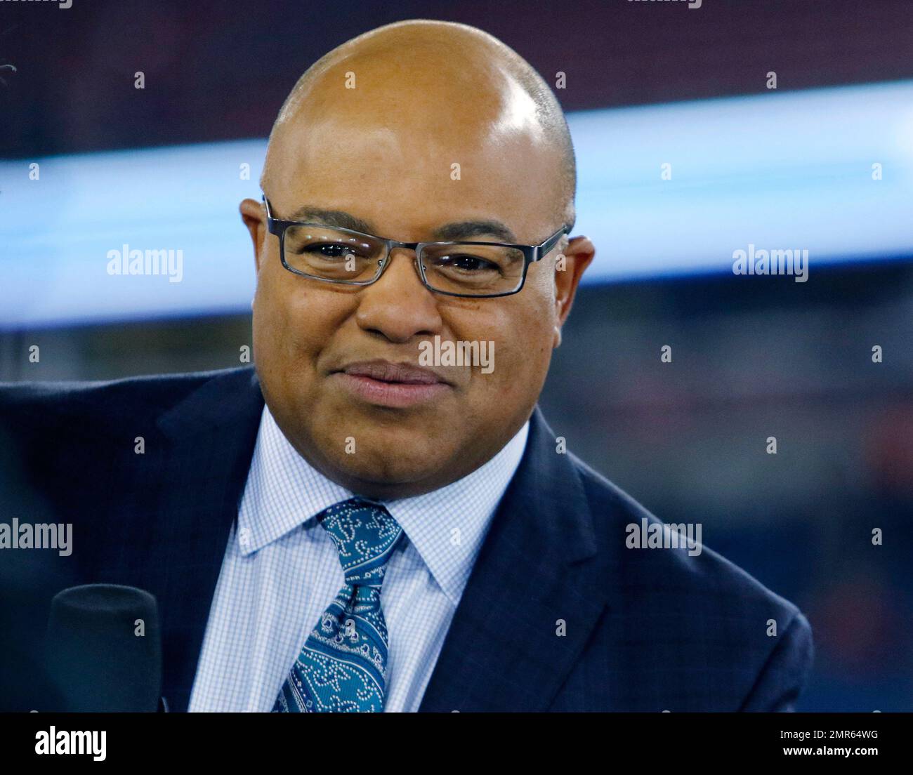 NFL sportscaster Mike Tirico sits on the sideline set before an NFL ...