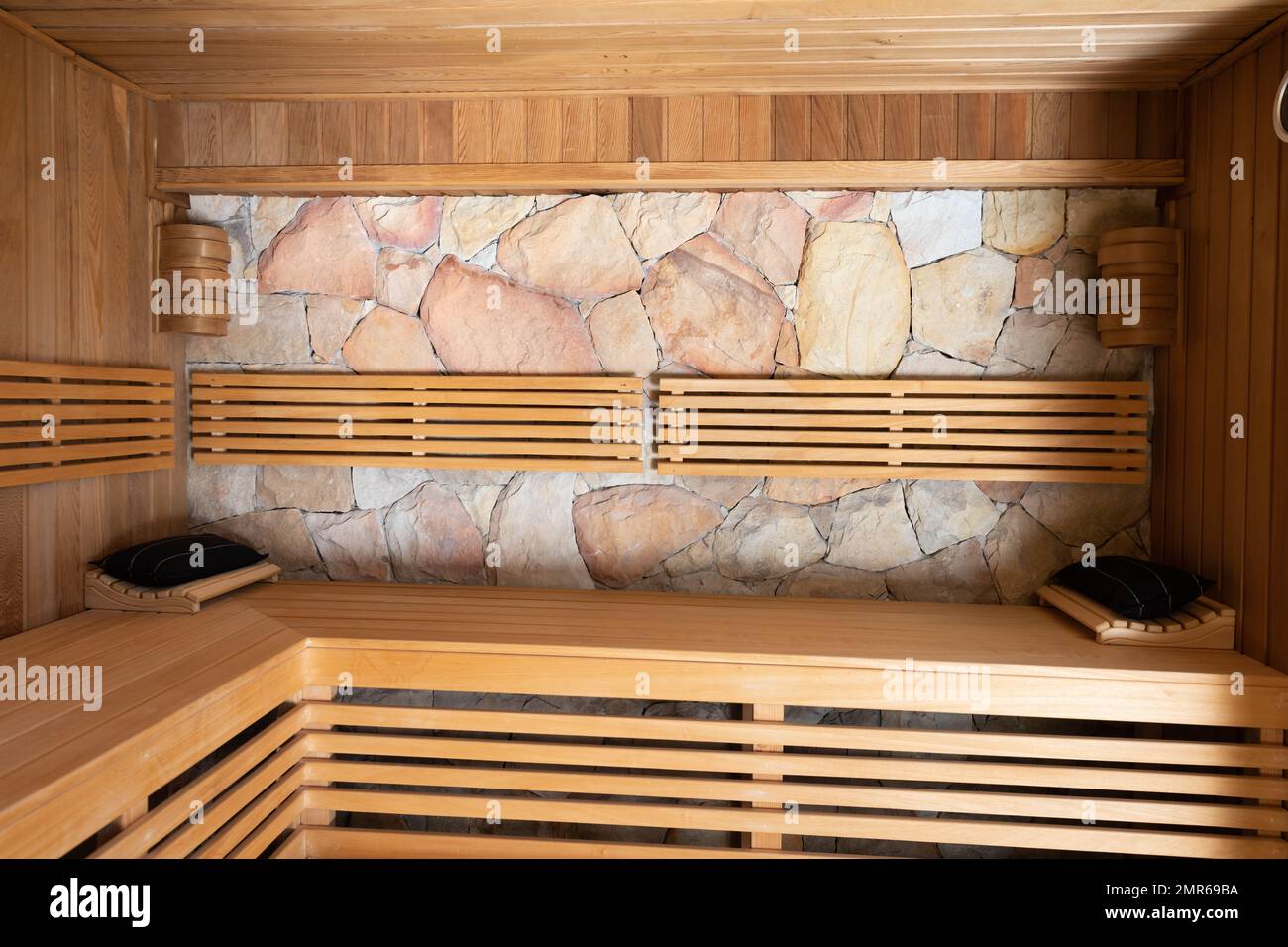General view of sauna with wooden benches and stone wall Stock Photo ...