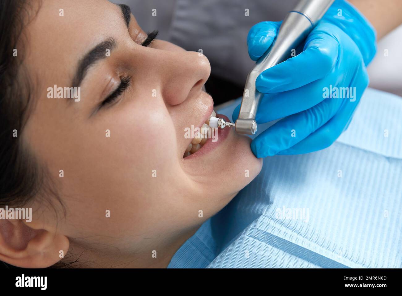 Young woman getting her teeth polished in dental clinic. Professional ...