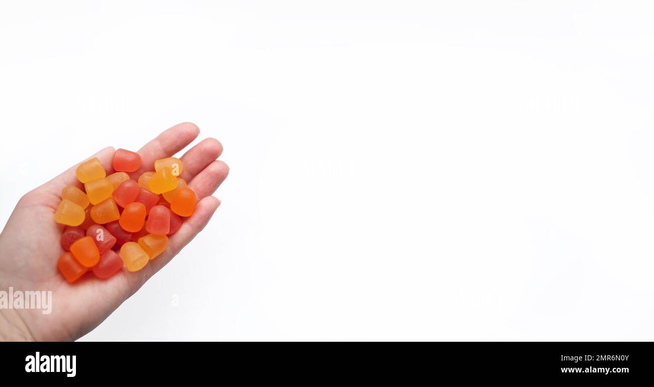 Group of red, orange and yellow multivitamin gummies in the hand ...