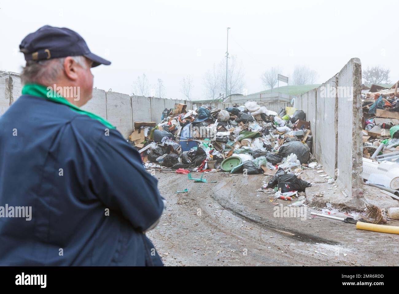 Recycling center worker, in dark blue work clothes, looking at an ...