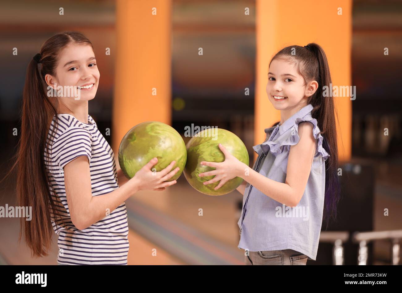 Happy girls with balls in bowling club Stock Photo - Alamy