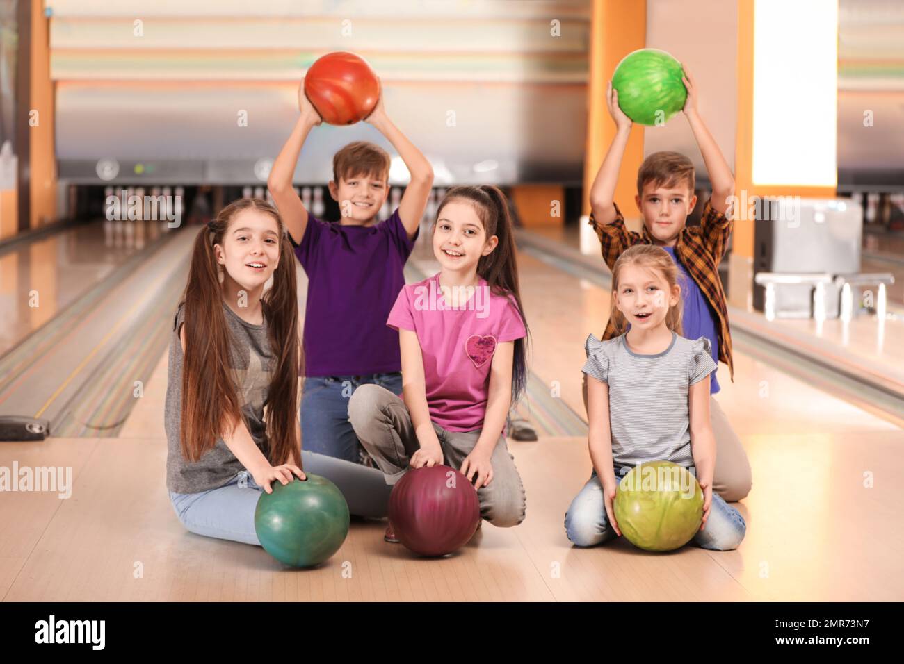 Happy children with balls in bowling club Stock Photo - Alamy