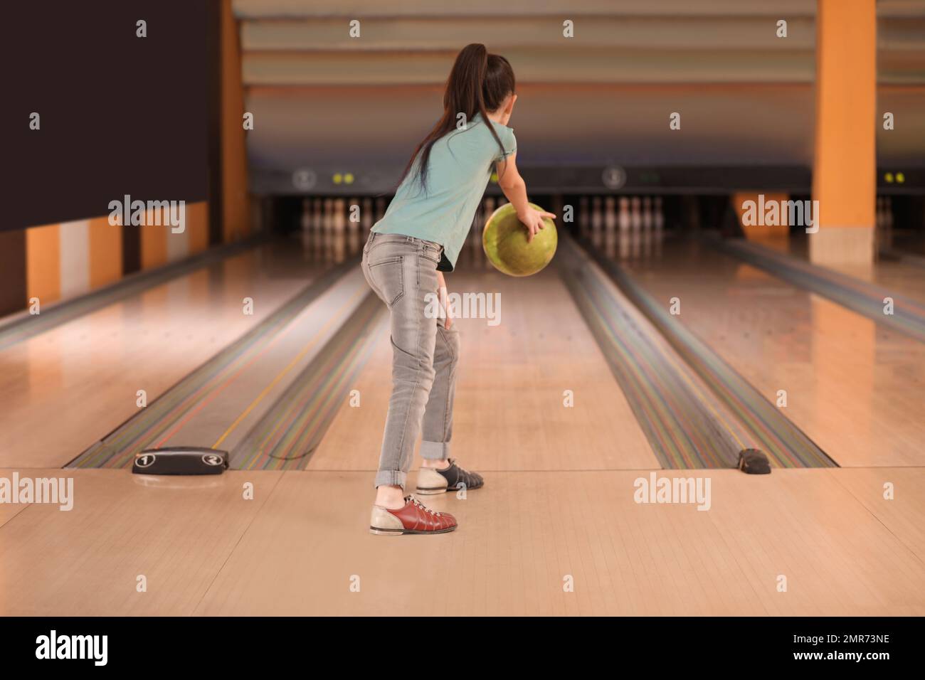 Little girl throwing ball at bowling club Stock Photo - Alamy