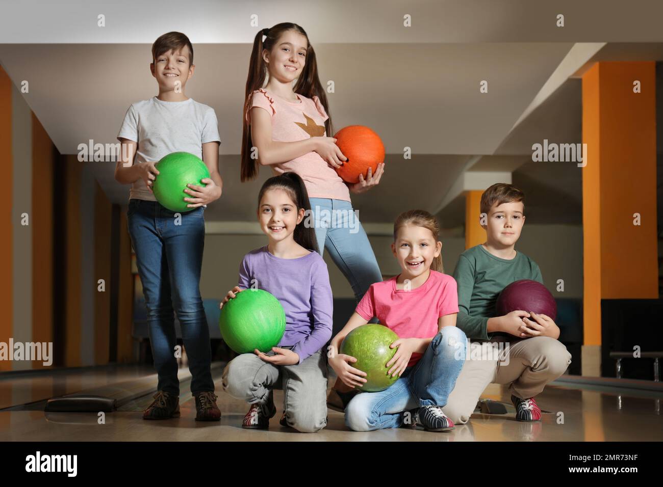 Happy children with balls in bowling club Stock Photo - Alamy