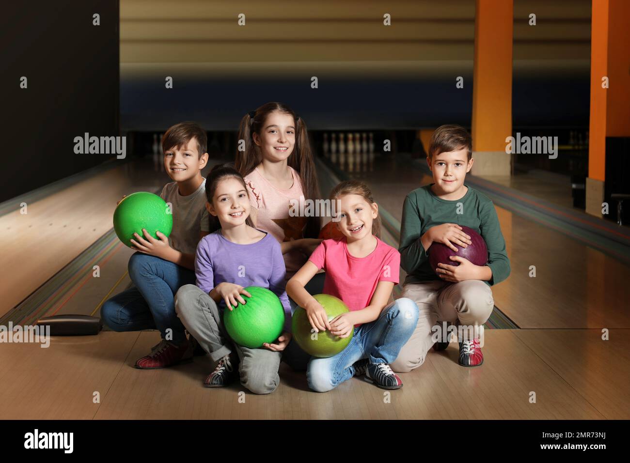 Happy children with balls in bowling club Stock Photo - Alamy